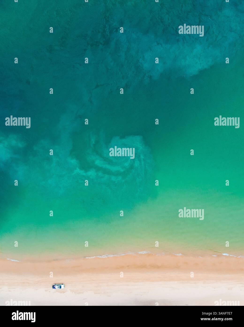 Aerial view of sandy beach with swirling whirlpool at Tangalooma Wrecks ...