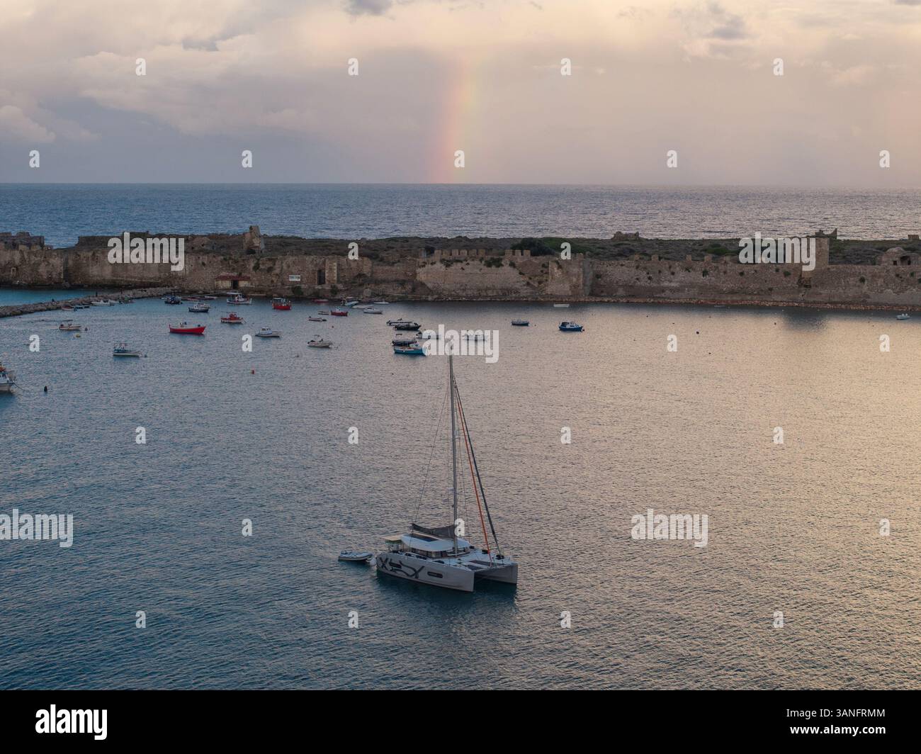Aerial view of ancient castle ruins and serene sea with boats under a ...