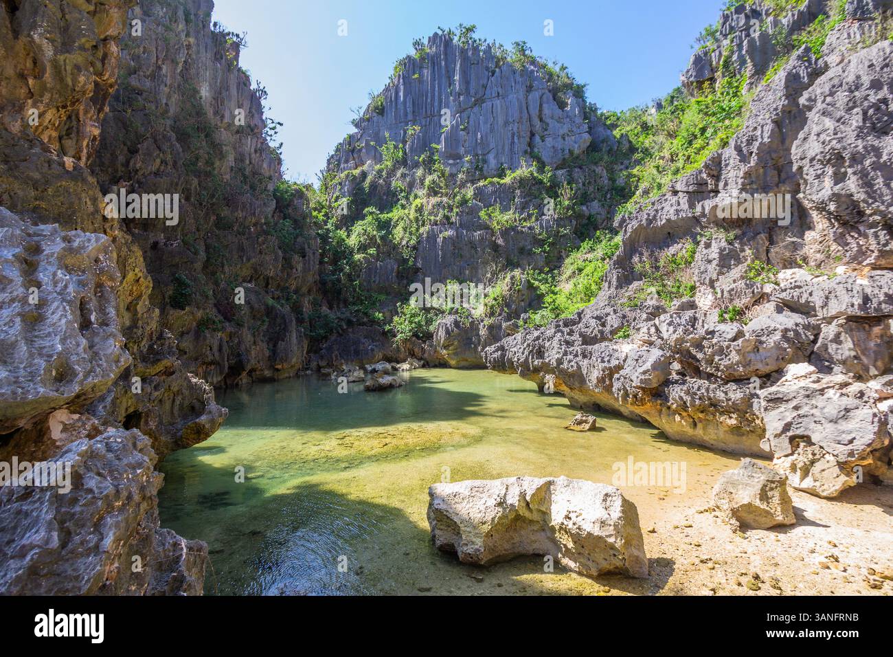 Tangke Saltwater Lagoon surrounded by towering limestone cliffs, a ...