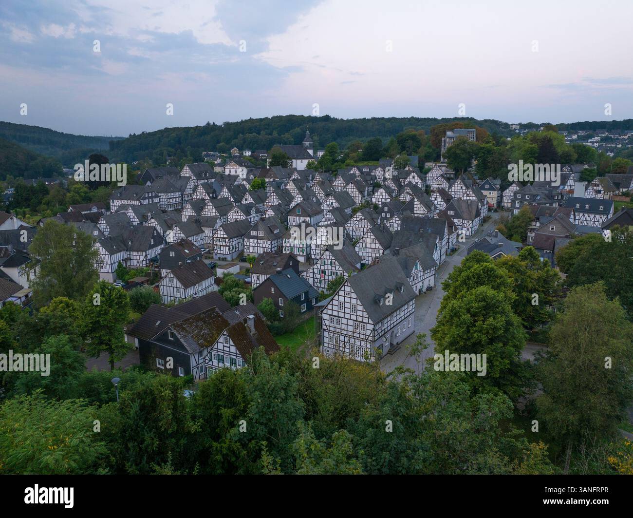 Aerial view of picturesque half-timbered houses in a charming village surrounded by greenery ...