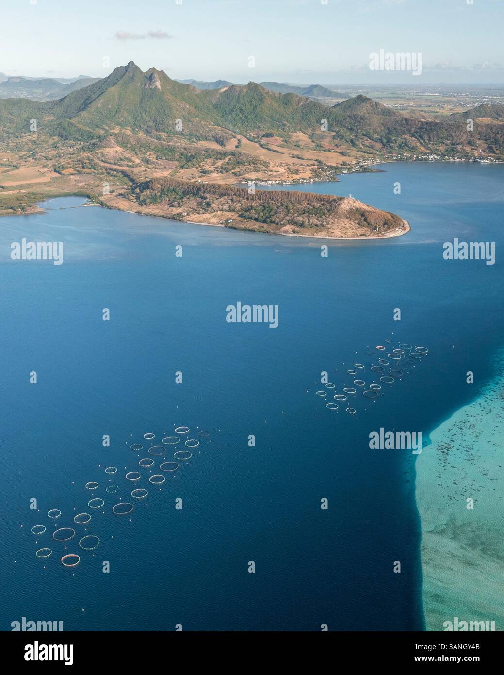 Aerial view of fish farm off the coastline with mountains in background ...