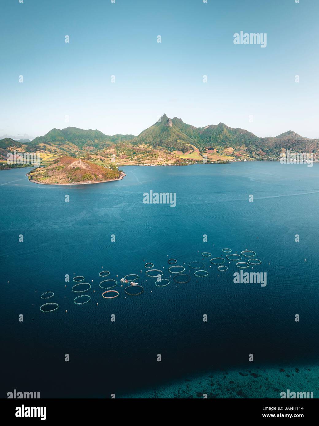 Aerial view of fish farm off the coastline with mountains in background ...