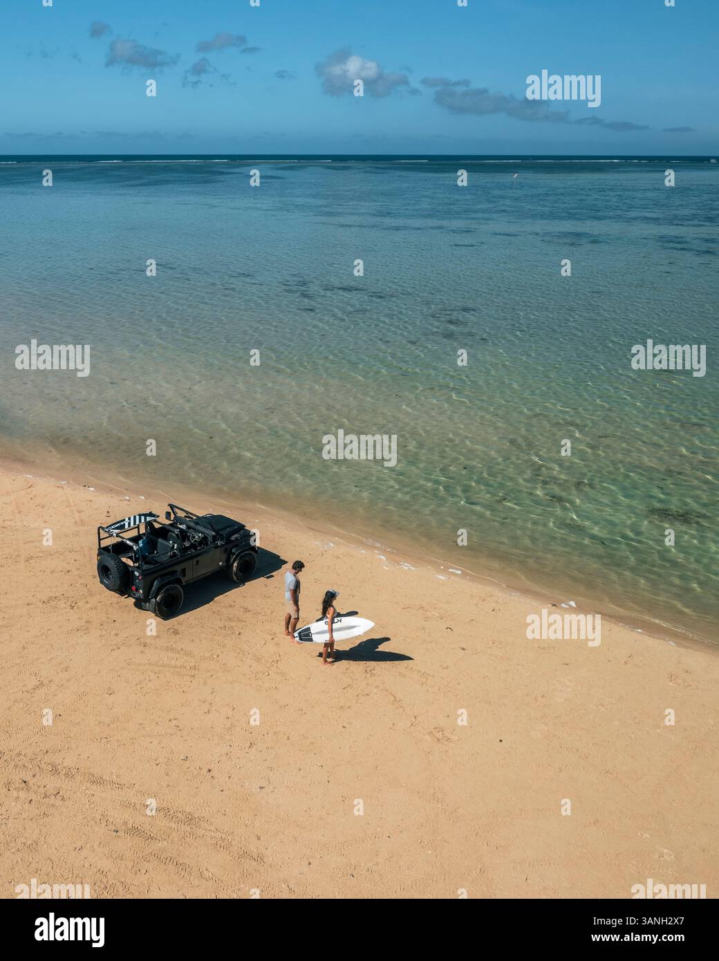Aerial view of an off road car parked along the shoreline on the beach ...