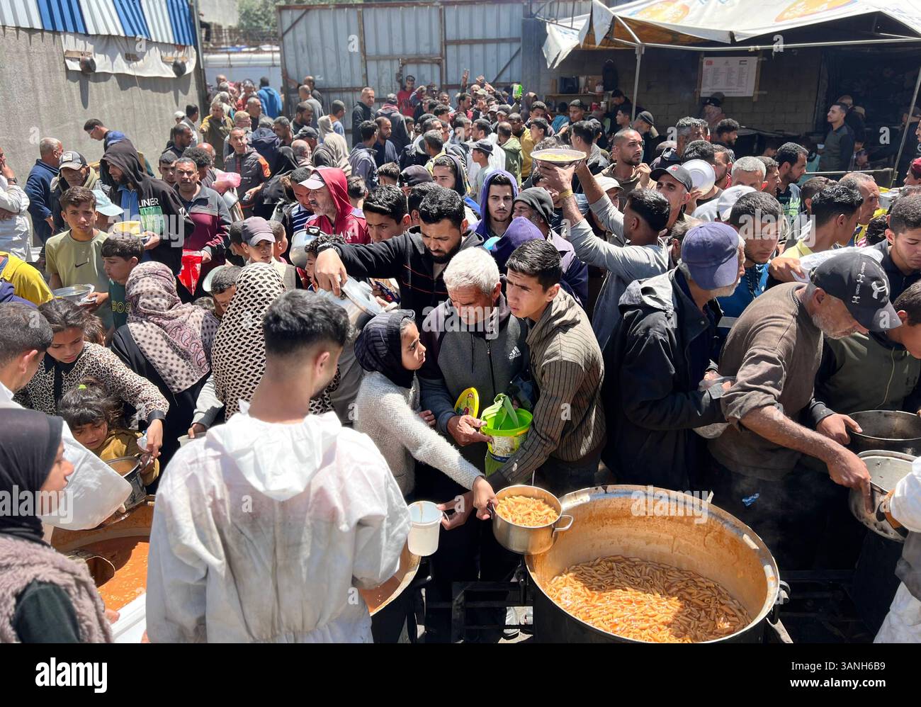 Palestinians gather in large numbers to receive the meals distributed ...