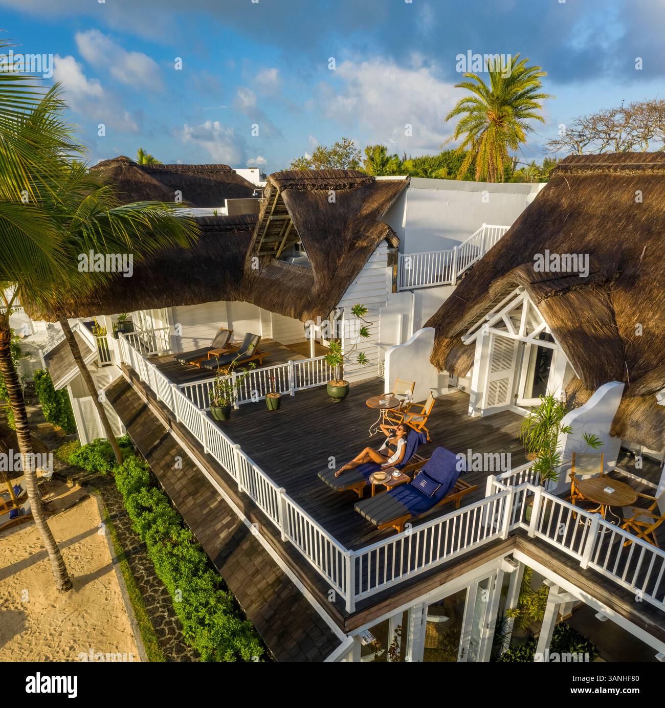 Aerial view of a woman relaxing on a balcony in a luxury resort in ...