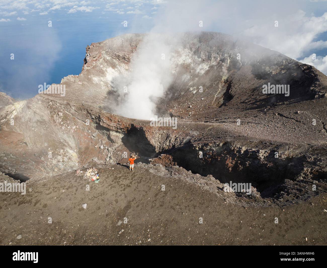 Aerial view of a person standing and looking over ledge of Gamalama ...