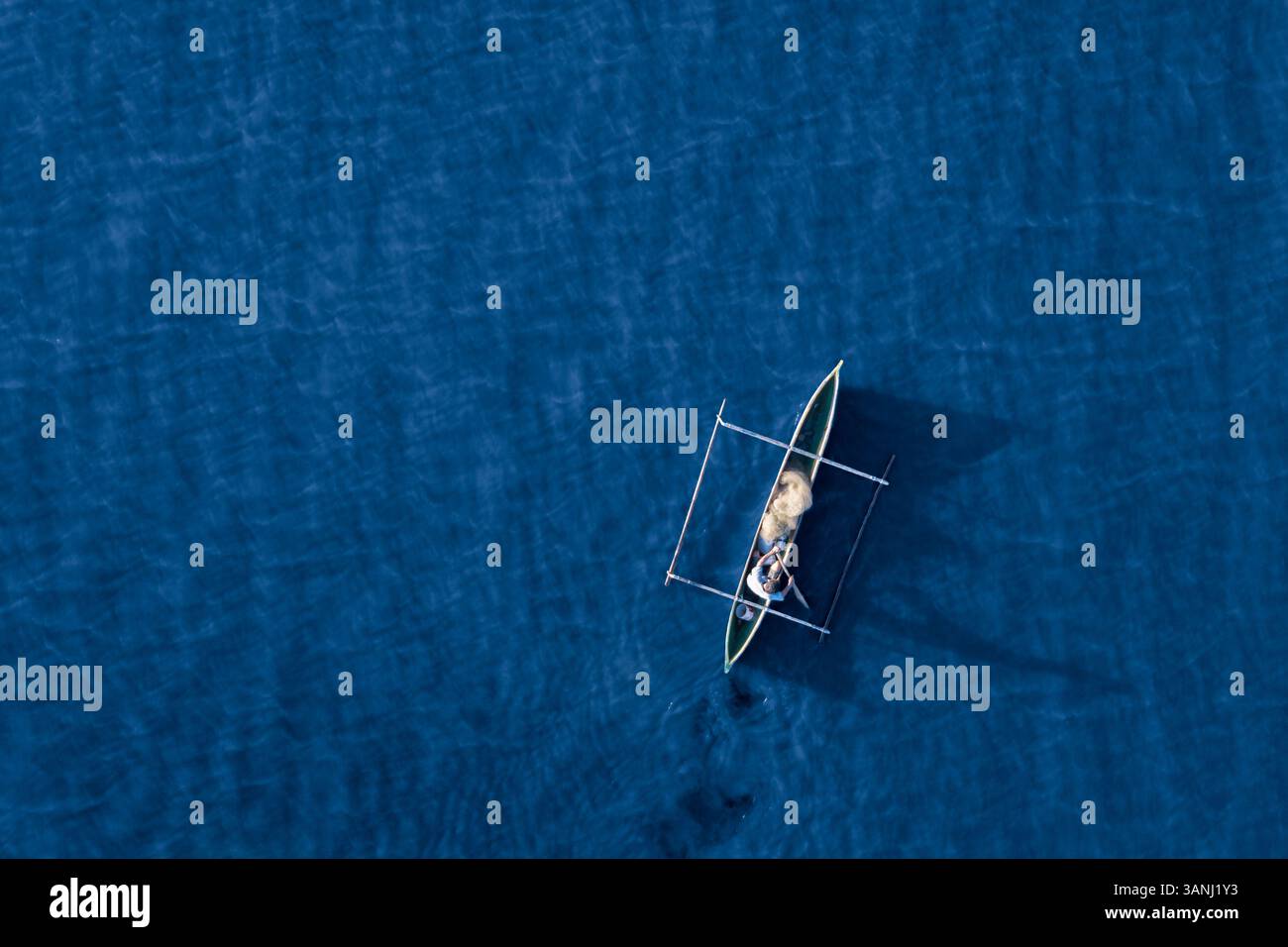 Aerial view of a fisherman and his mirror shadow fishing using a ...