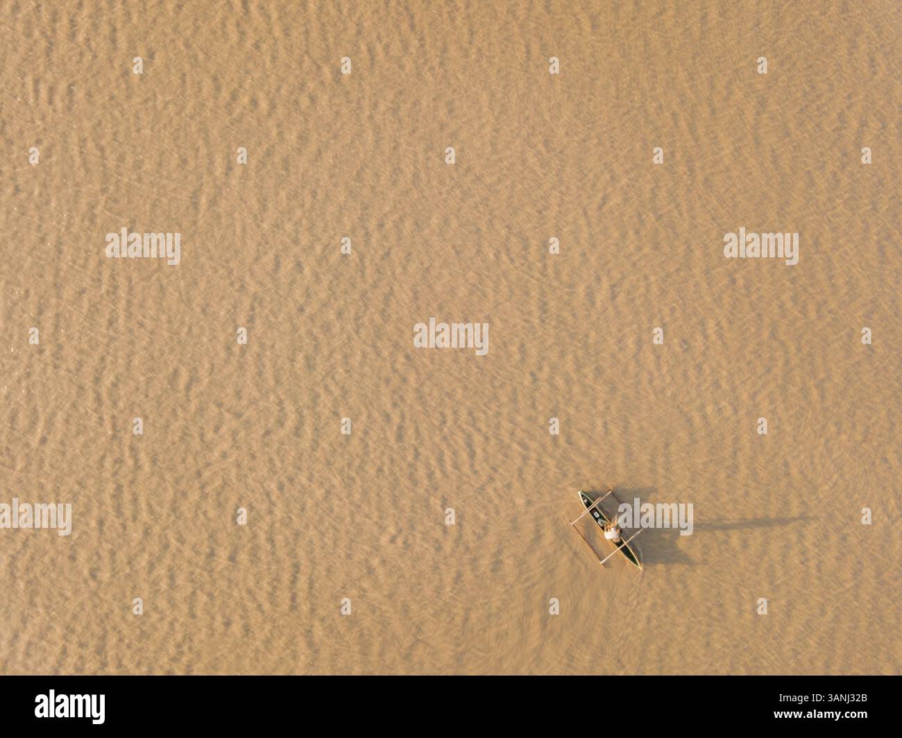 Aerial view of a fisherman and his mirror shadow fishing using a ...