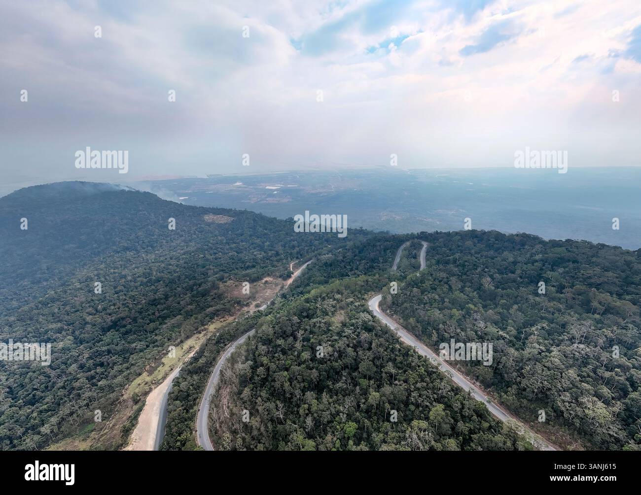 Aerial view of a winding road through lush forest and mountainous ...