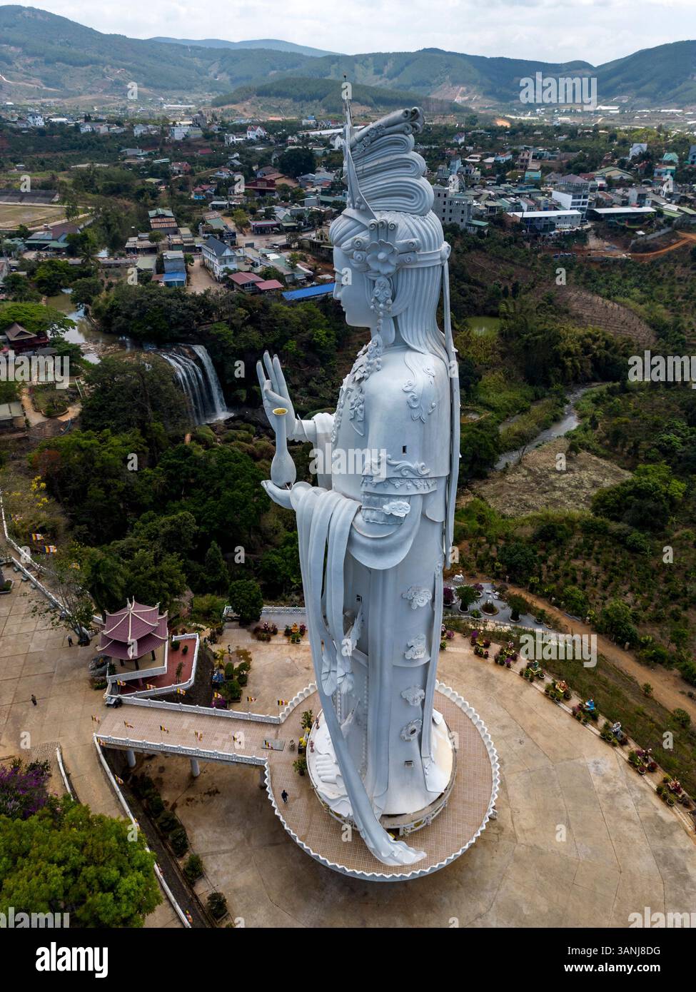 Aerial view of a sacred Buddha statue beside a scenic waterfall and ...