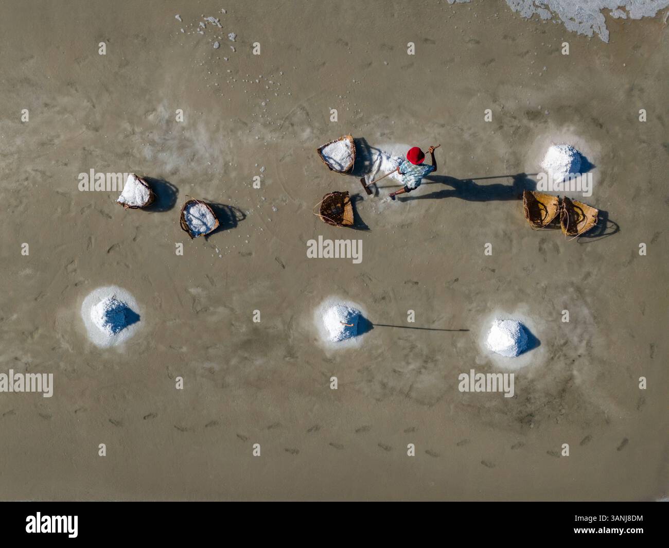 Aerial view of salt harvesting with workers and salt piles in a ...