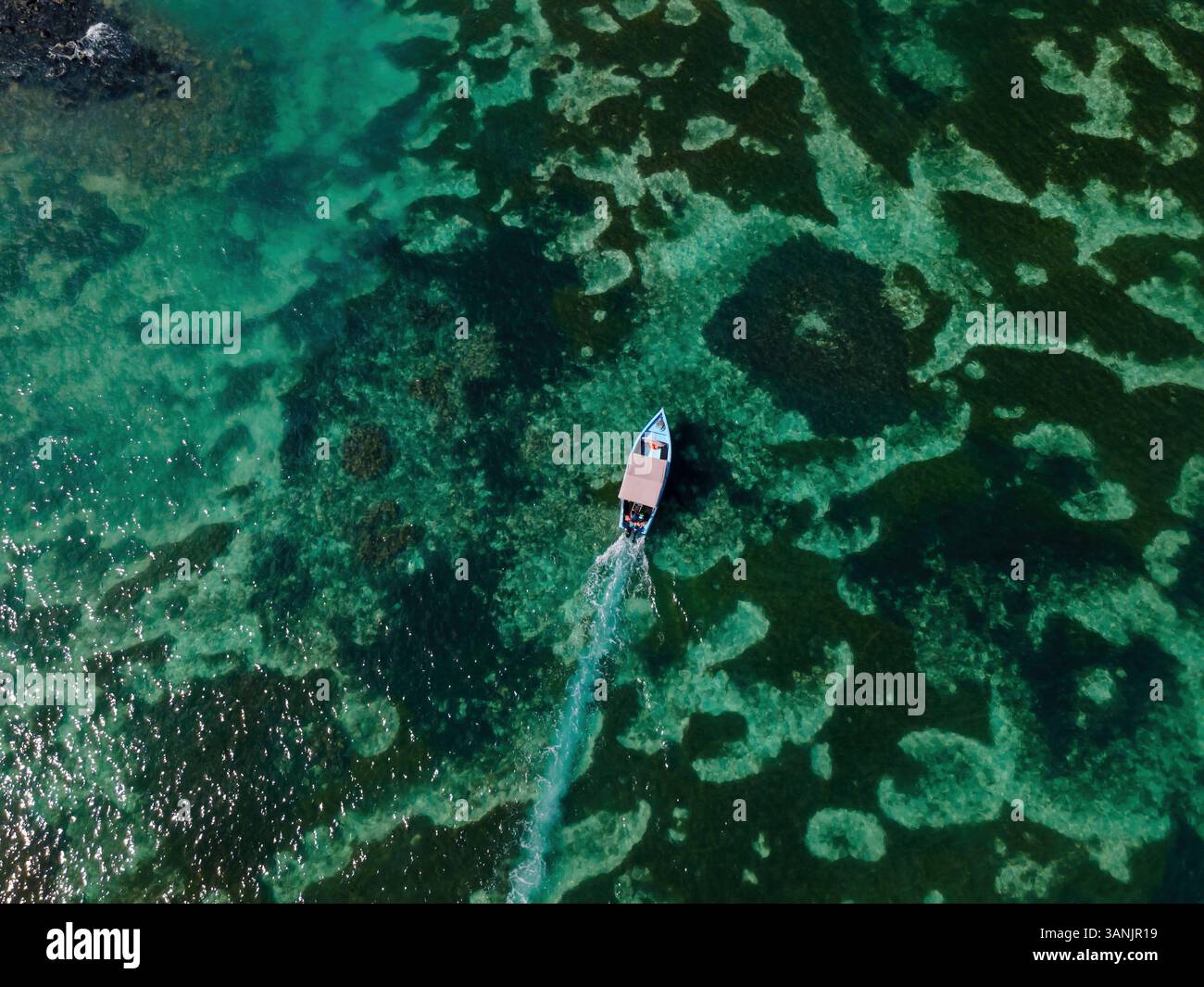 Aerial view of small fishing boat on crystal clear blue ocean, Pointe ...