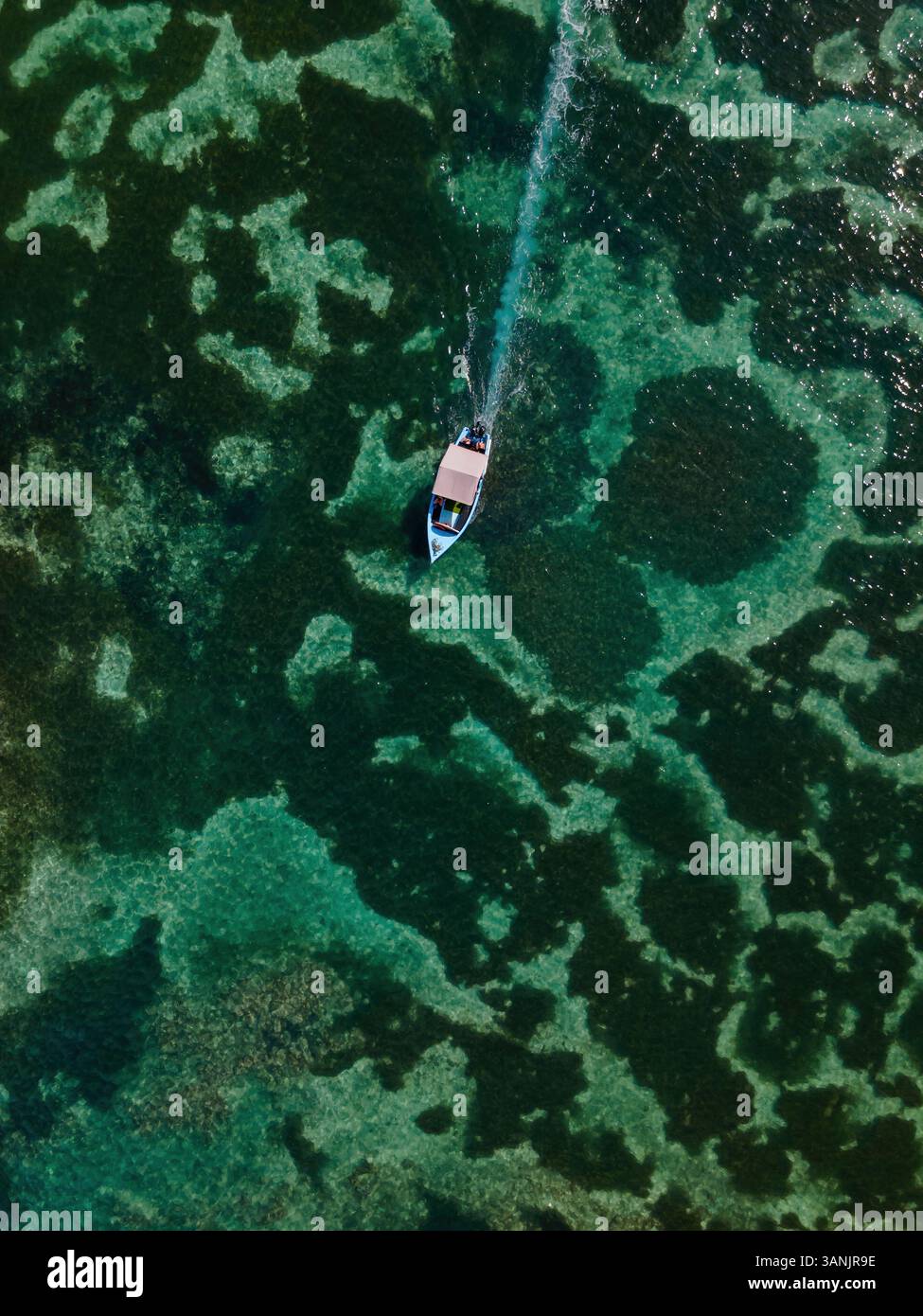 Aerial view of small fishing boat on crystal clear blue ocean, Pointe ...