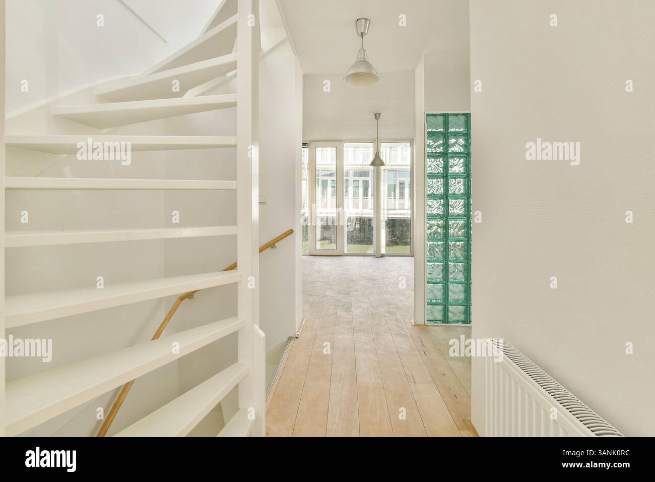 A sleek and bright hallway featuring a modern staircase, large windows ...