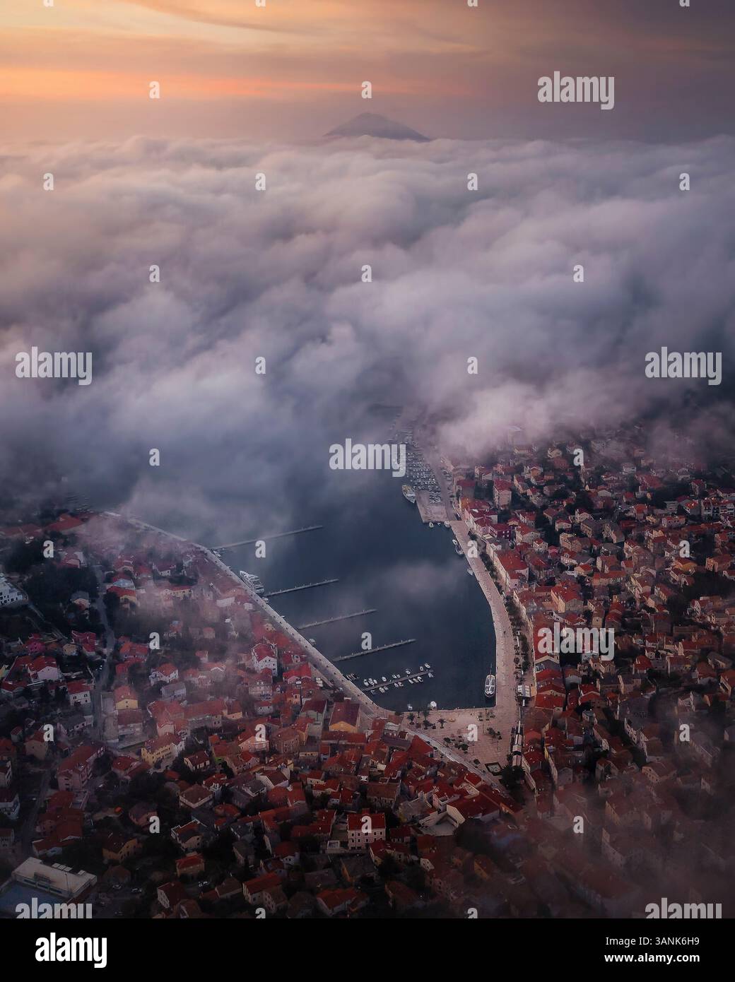 Aerial view of a foggy coastline with a historic town and marina, Veli ...