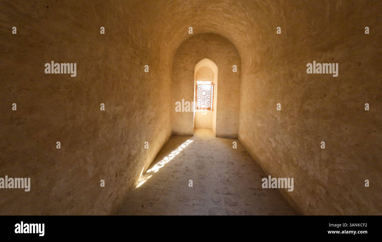 A narrow, dimly lit corridor with an arched ceiling and a small, ornate ...