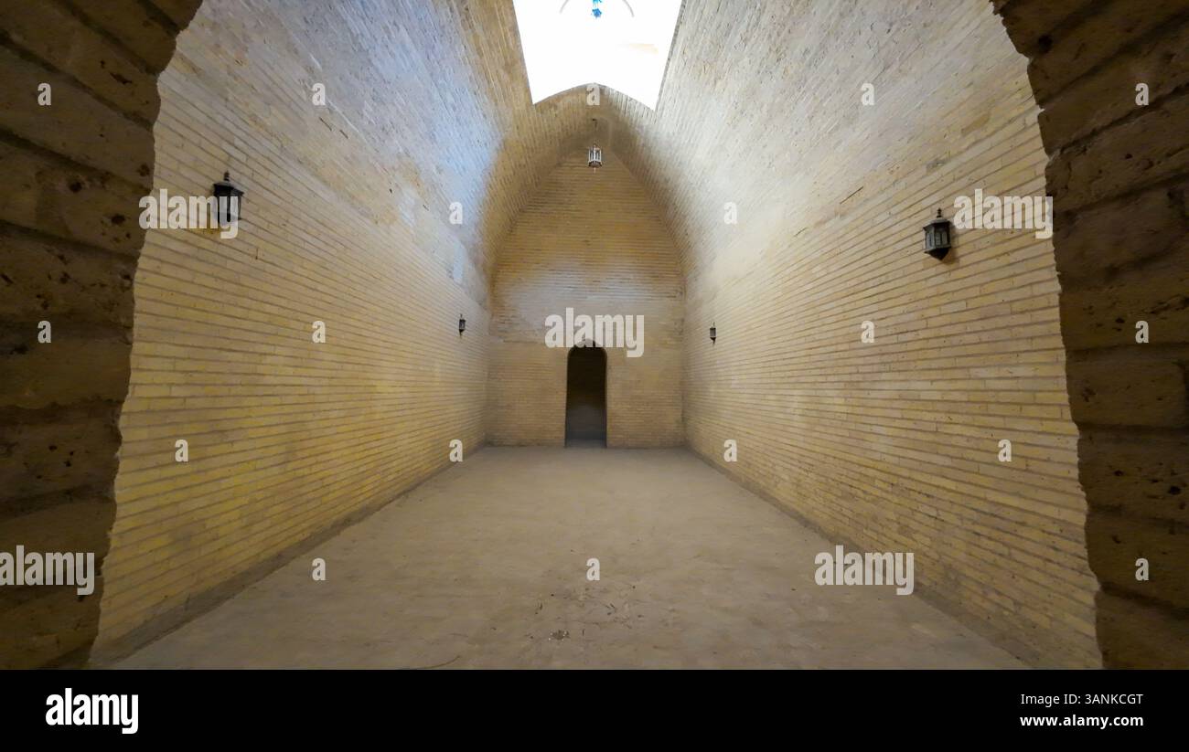 A long, narrow brick hallway with arched ceiling and lanterns on the ...