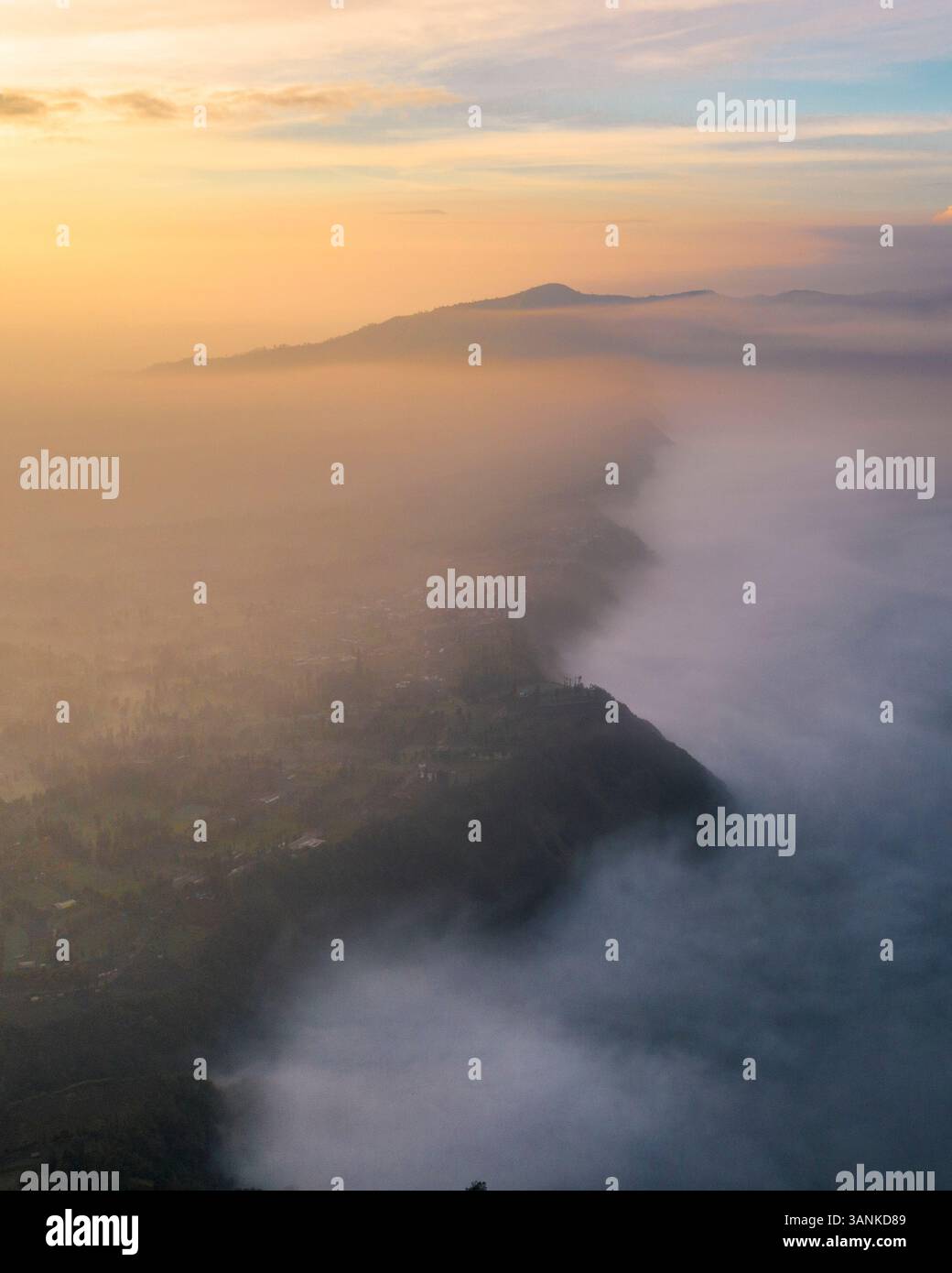 Aerial view of majestic mountains shrouded in mist and clouds at dawn ...