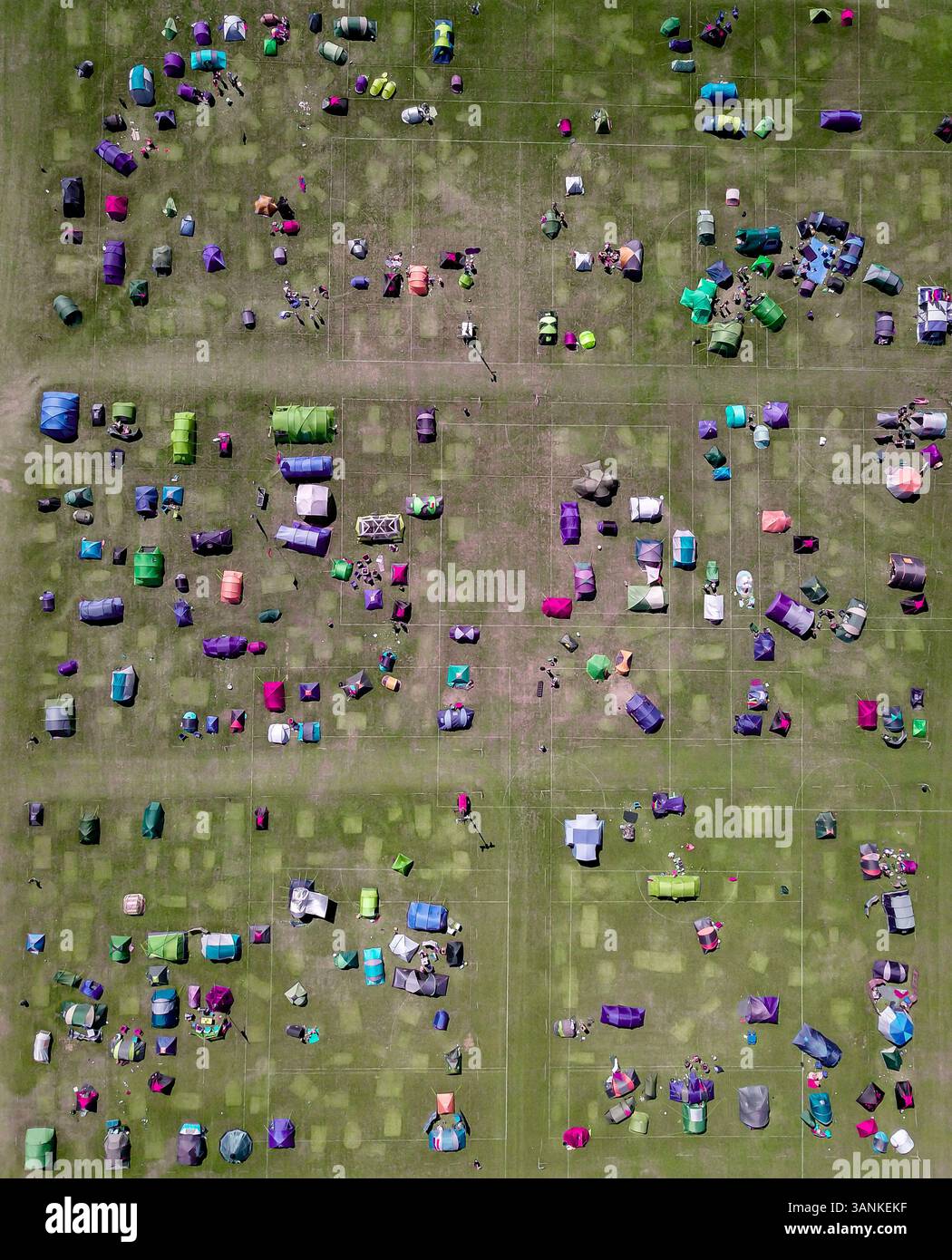 Aerial view of a colorful campsite with tents set on lush grass ...