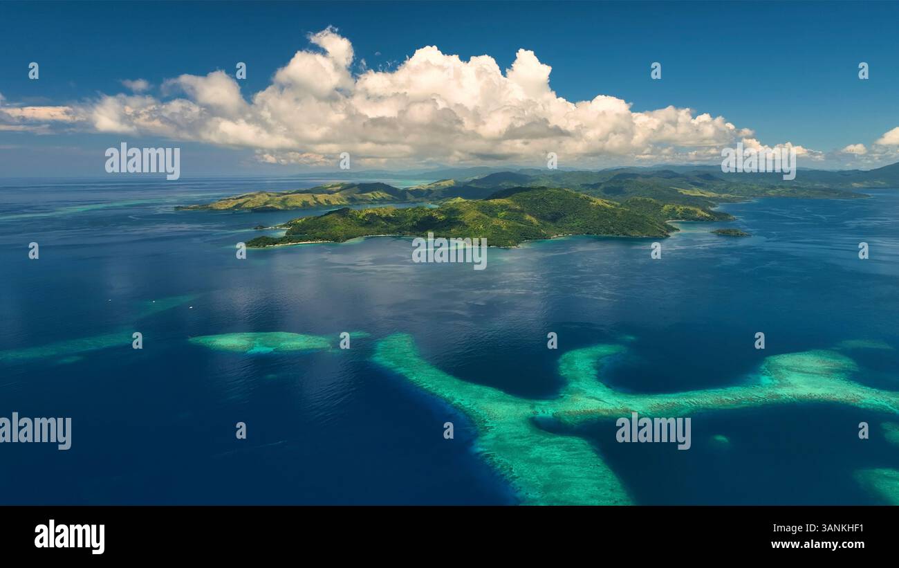 Aerial view of tropical island with reef and clouds over the ocean ...