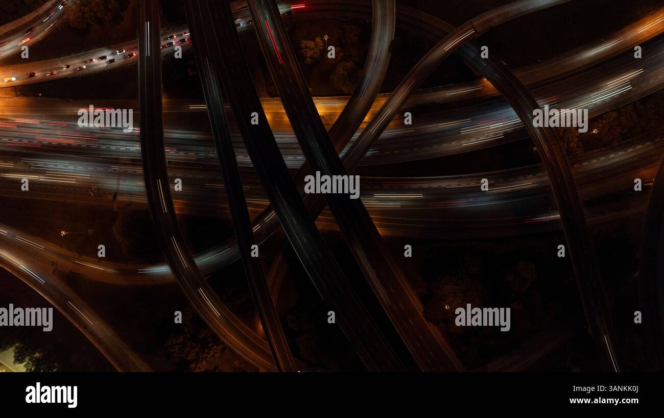 Aerial view of busy highway interchange with traffic and city lights at ...