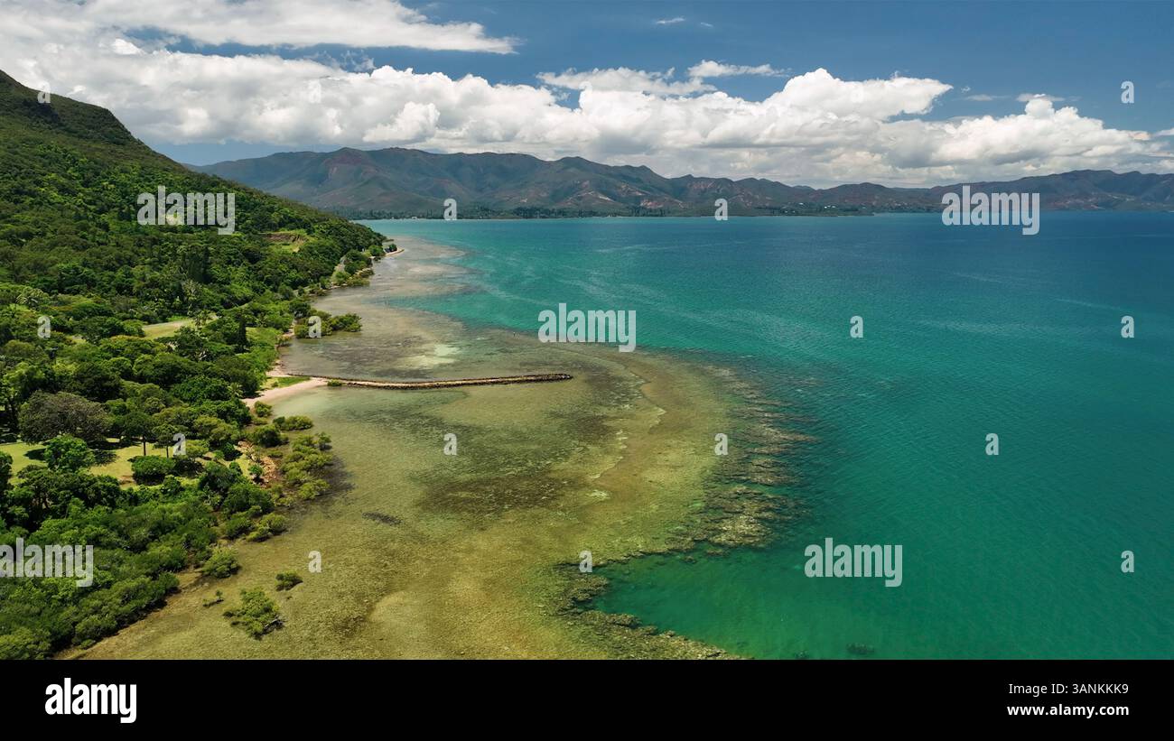 Aerial view of coastal island with blue ocean, lush greenery, and ...