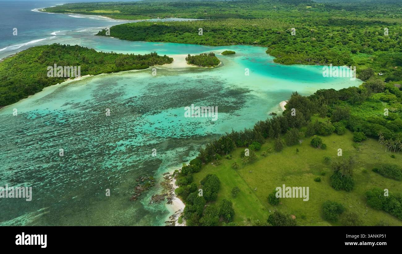 Aerial view of a tropical island with lush greenery, reefs, and waves ...