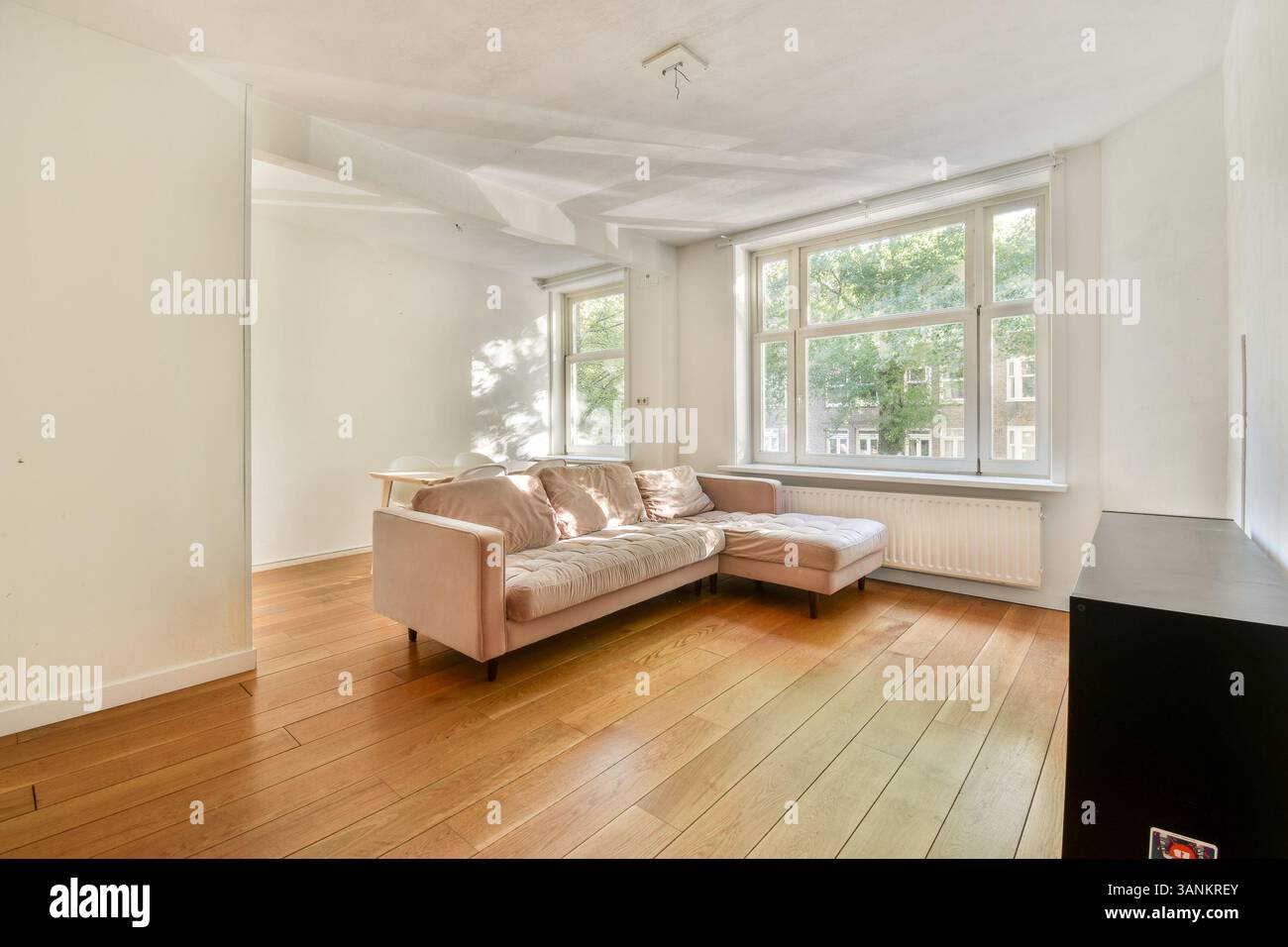 A spacious and bright living room featuring a light-colored couch and ...