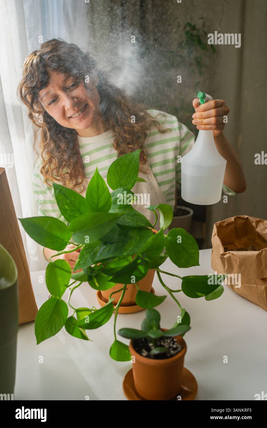 Woman spraying houseplant near window hi-res stock photography and ...