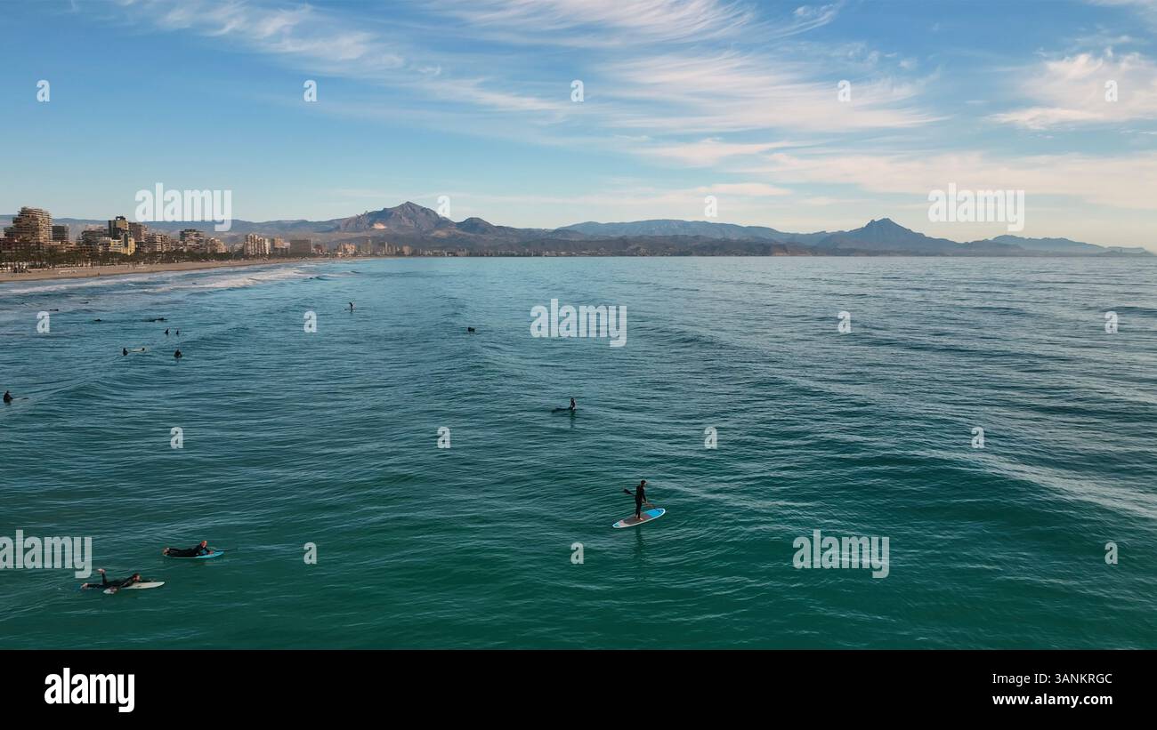 Aerial view of surfers riding waves along a beautiful coastal beach ...