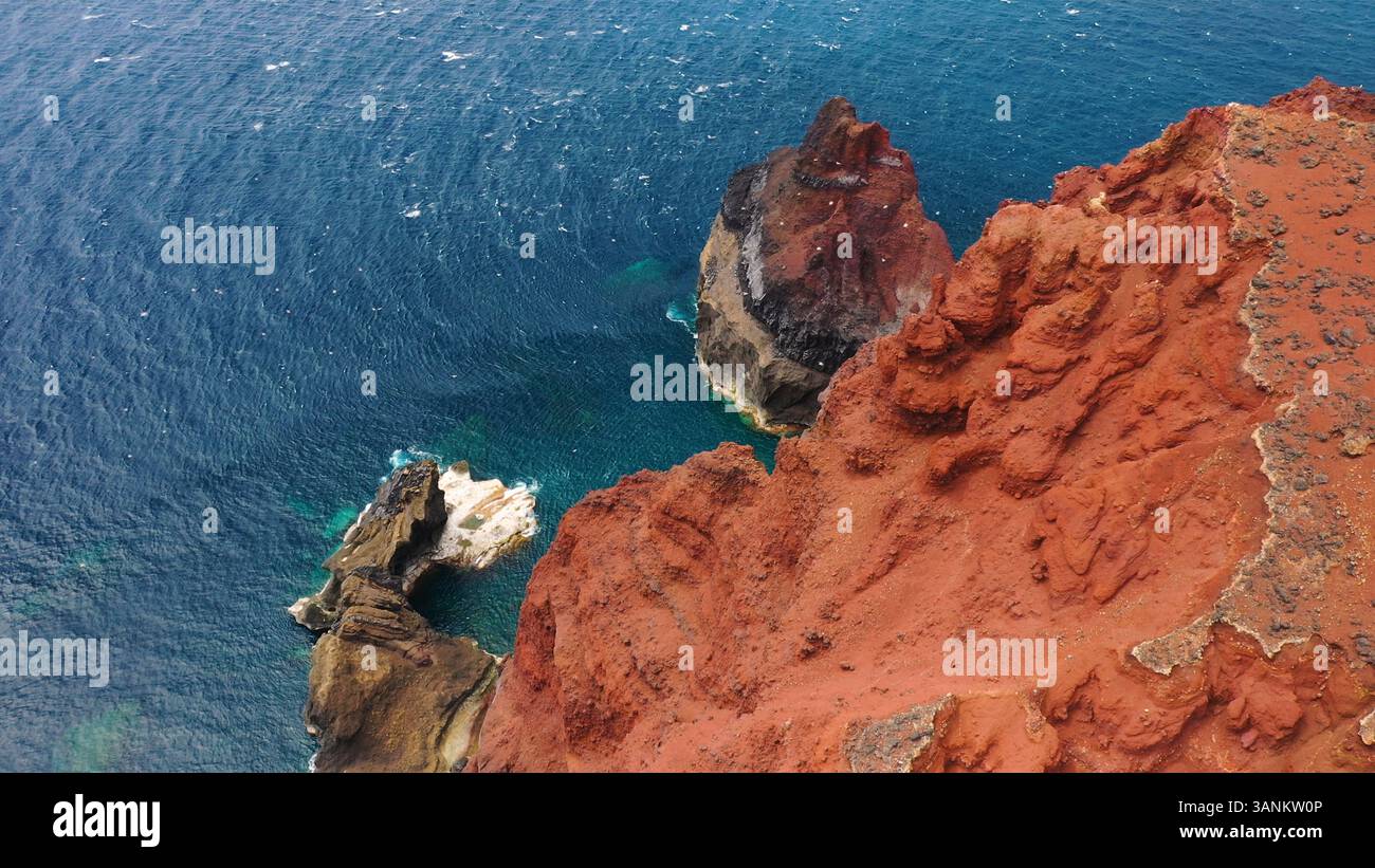Aerial view of dramatic cliffs and a vibrant ocean surrounding a ...