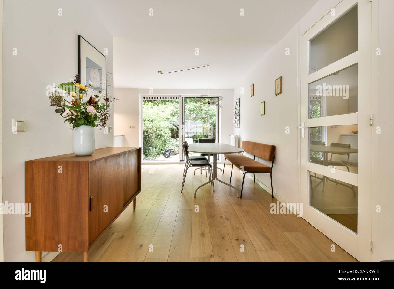 Bright and airy interior featuring a wooden sideboard, a dining table ...