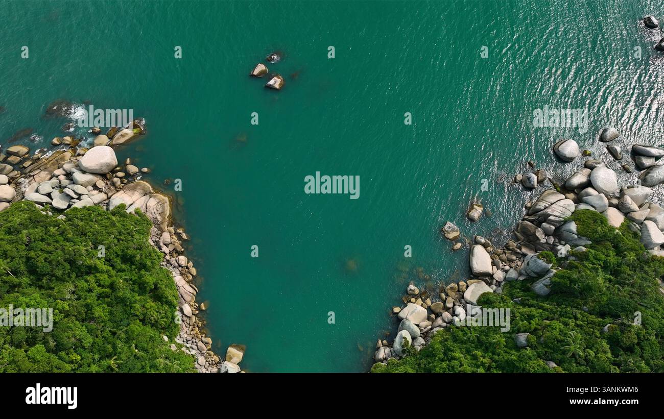Aerial view of beautiful turquoise water and rocky shore with lush ...