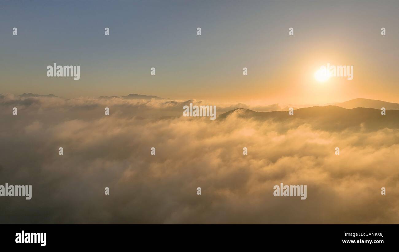 Aerial view of tranquil sunset over majestic mountains and soft clouds ...