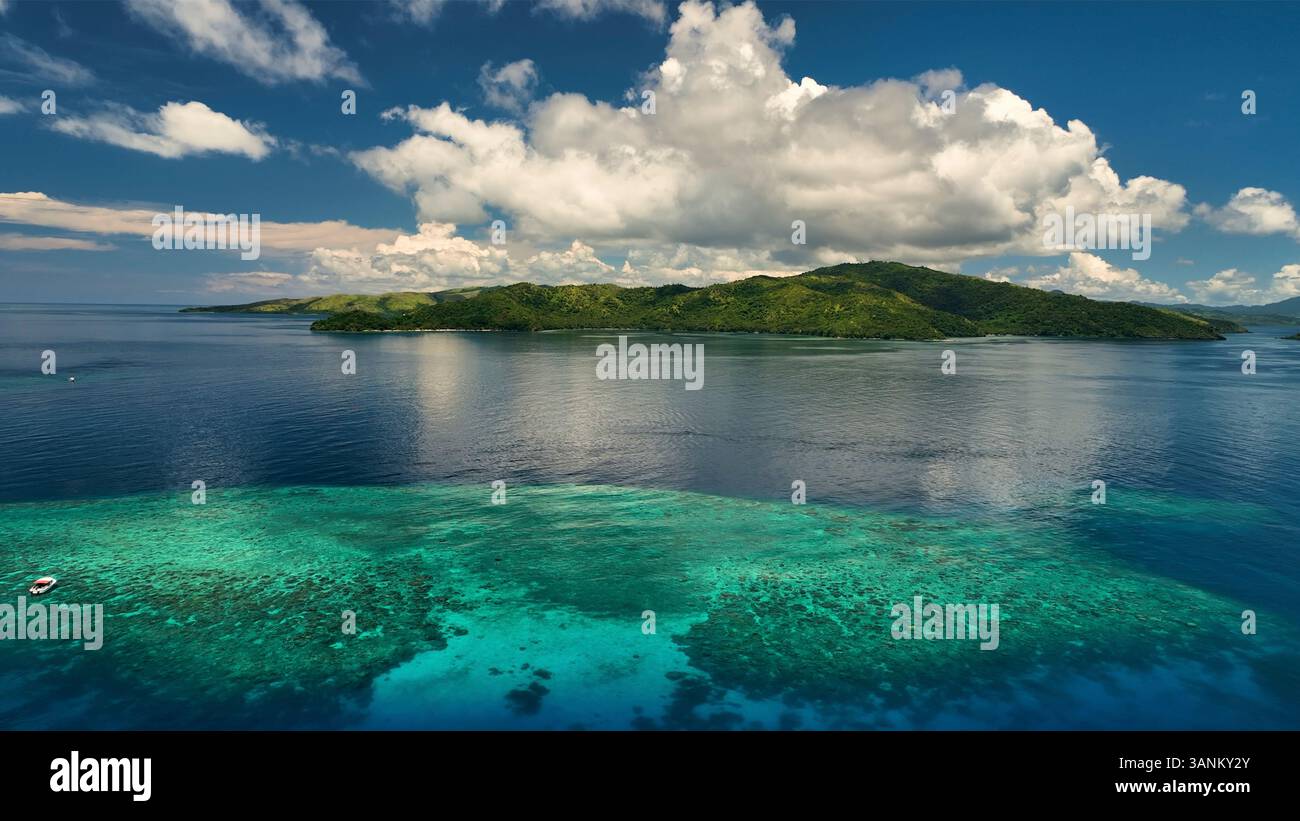 Aerial view of tropical island with crystal clear water, reef, and ...
