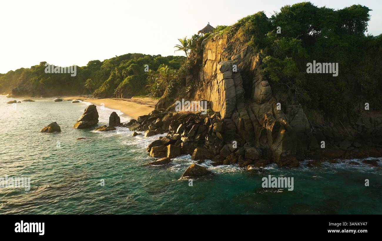 Aerial view of tropical beach with turquoise water, cliff, rocks, and ...