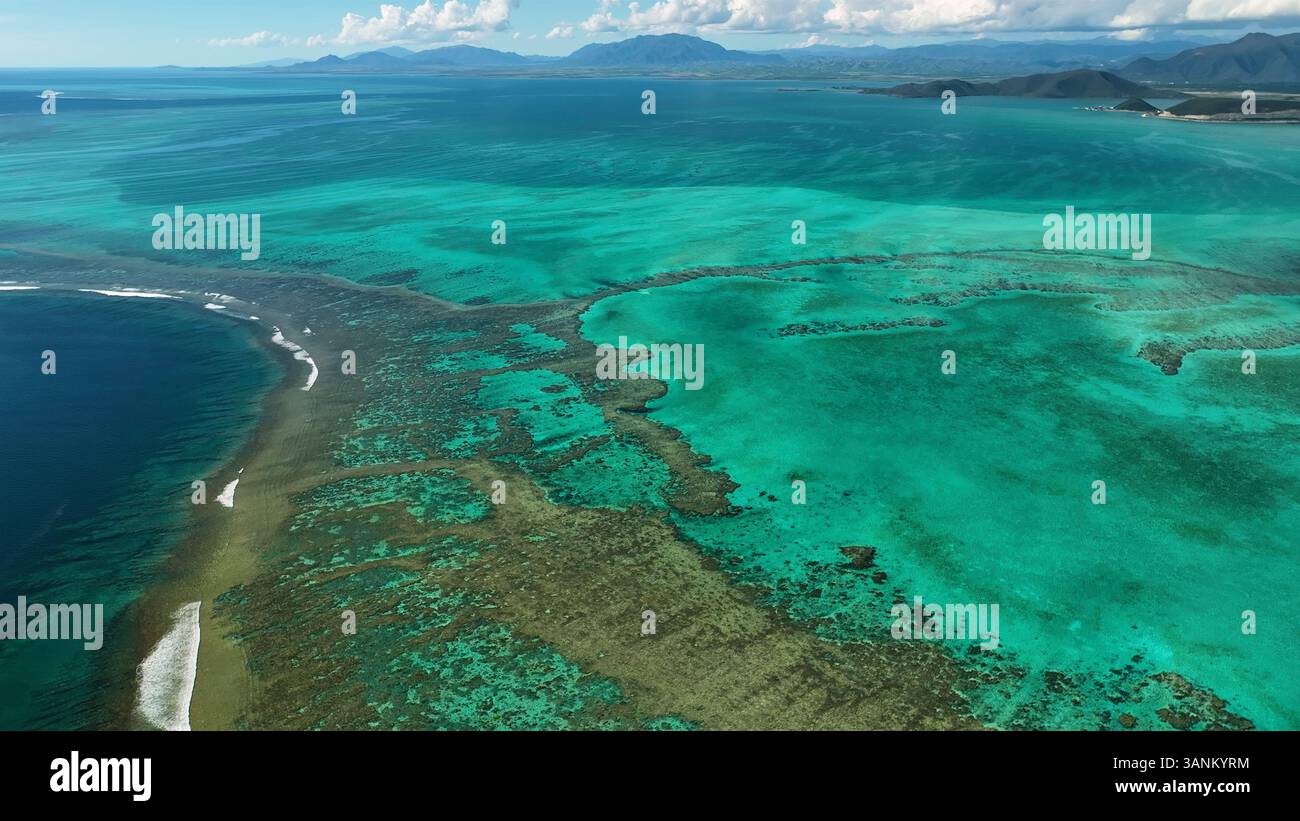 Aerial view of turquoise reef and ocean coast with mountains under a ...