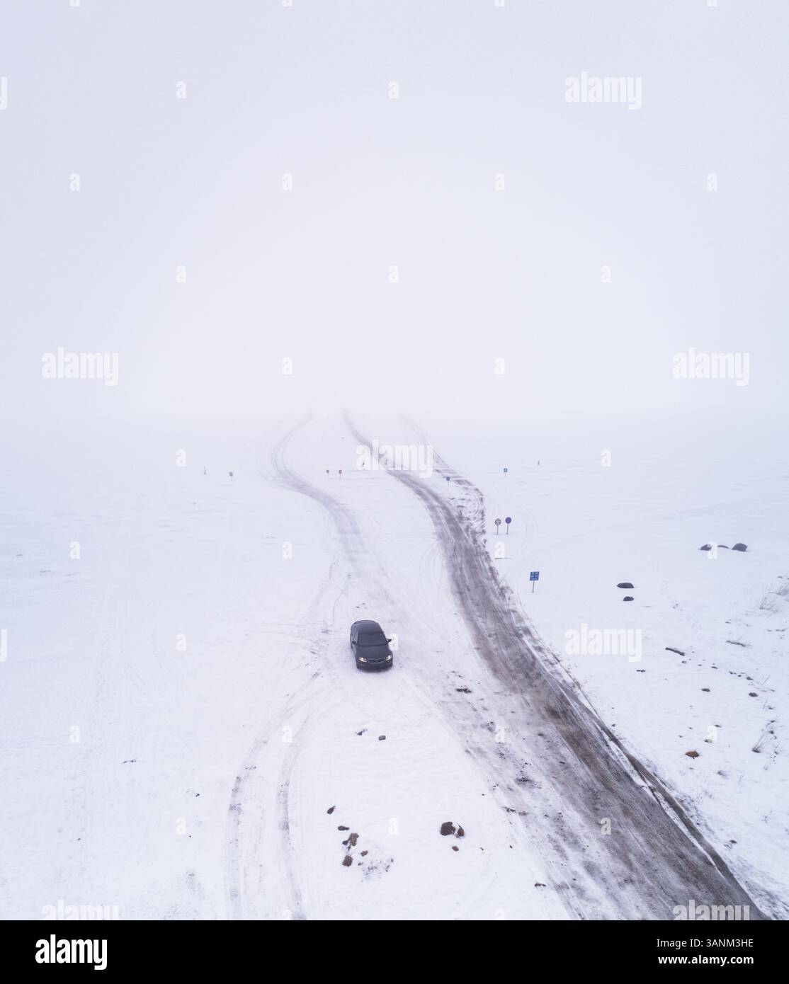Aerial view of a car driving on a frozen road in the Blizzard in ...