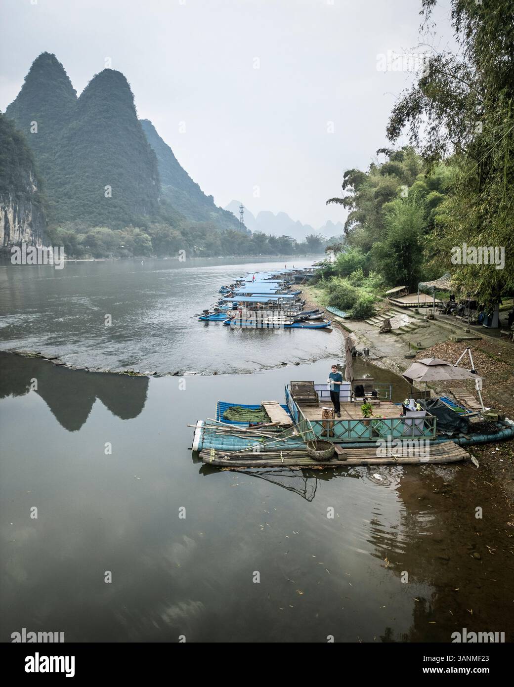 Aerial view of serene karst mountains and a tranquil river with boats ...