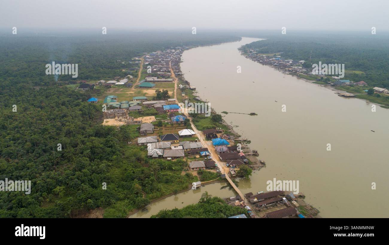 Aerial view of a serene village by a river surrounded by lush tropical ...