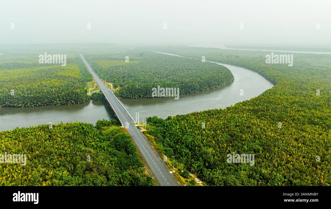 Aerial view of a winding river and highway surrounded by lush greenery ...