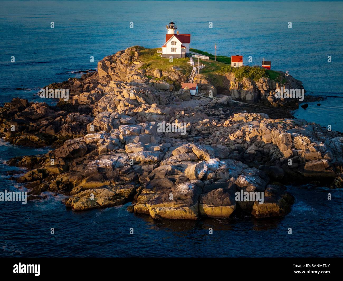 Aerial view of nubble lighthouse on a rocky coast with serene ocean ...