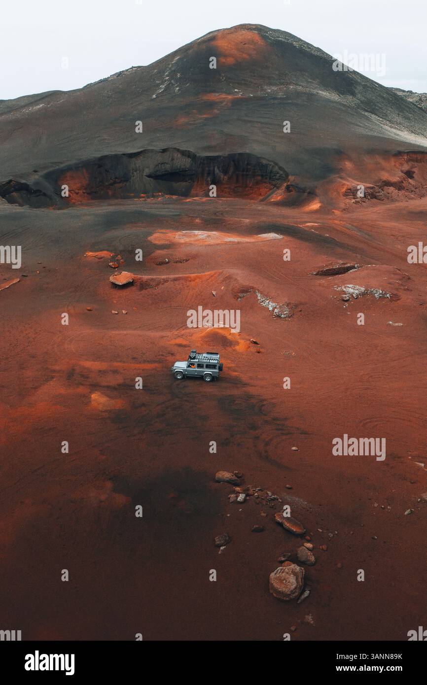 Aerial view of rugged volcanic area with Land Rover Defender on barren ...