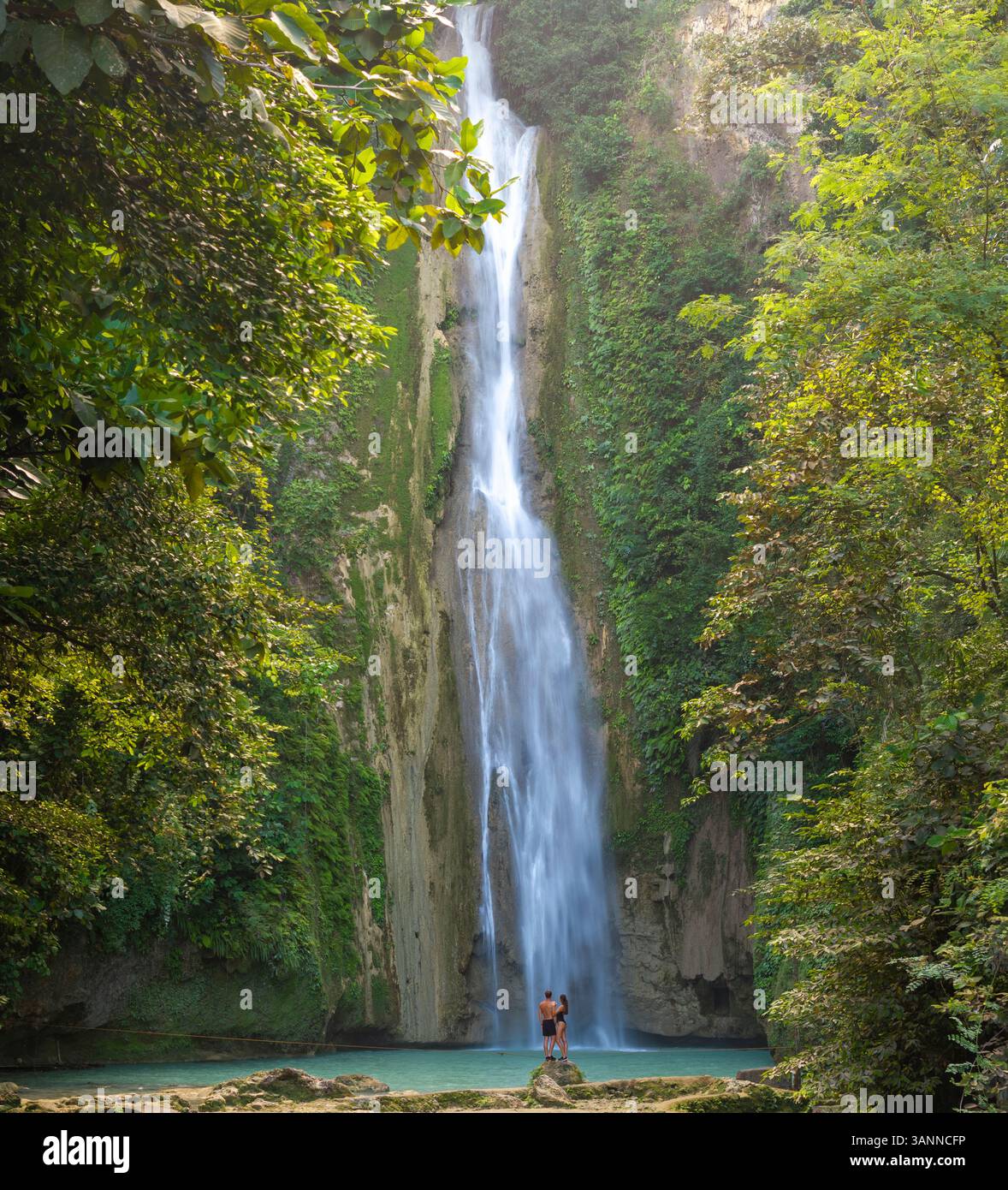 Aerial view of mantayupan falls with a couple standing on a rock ...