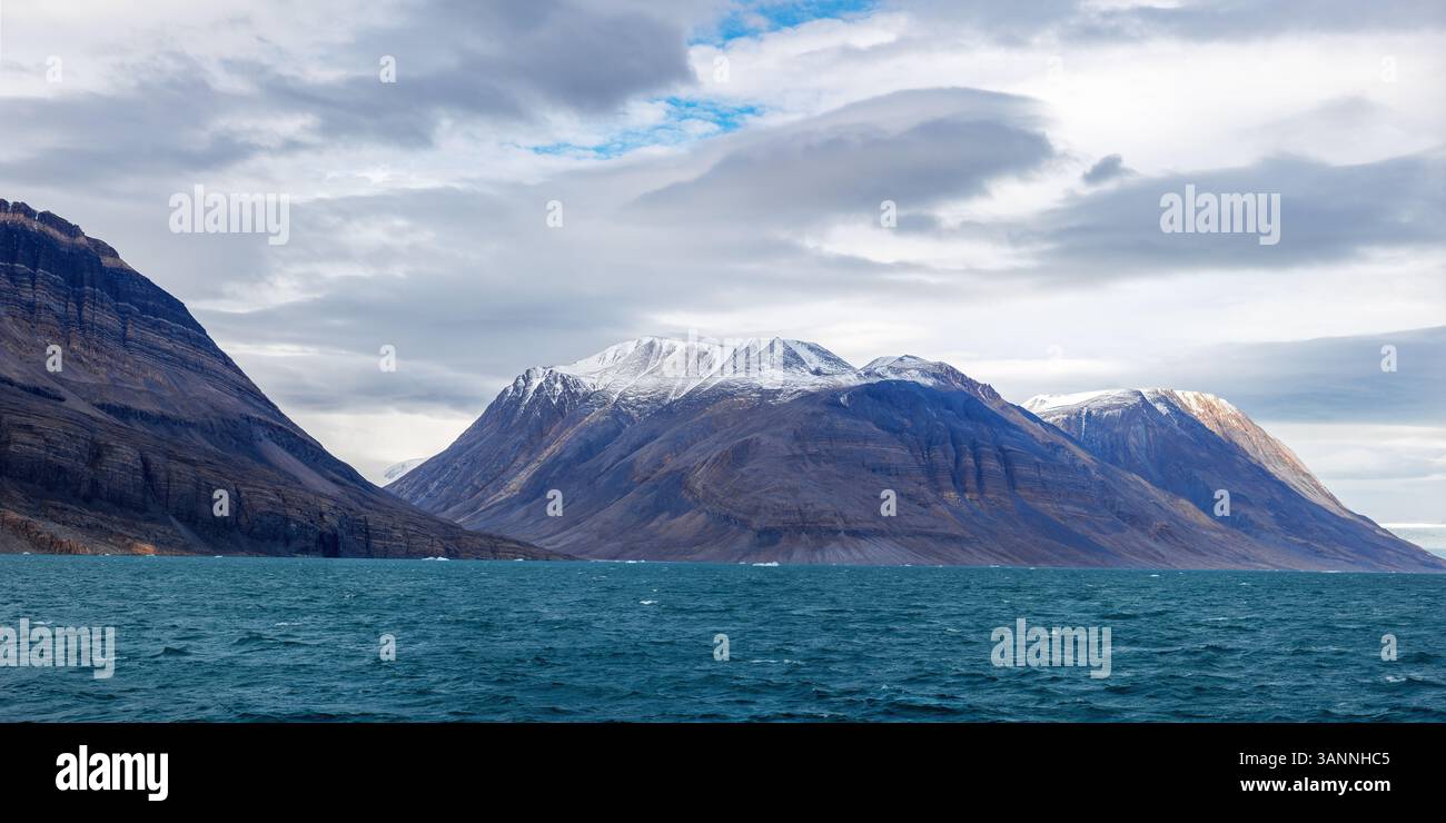 A panorama of the snow covered mountains and blue waters of Geologfjord ...