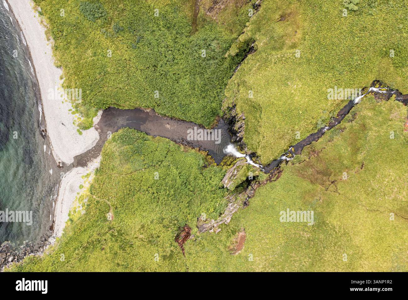 Aerial view of a waterfall along the coast in Broad Bay, Unalaska ...