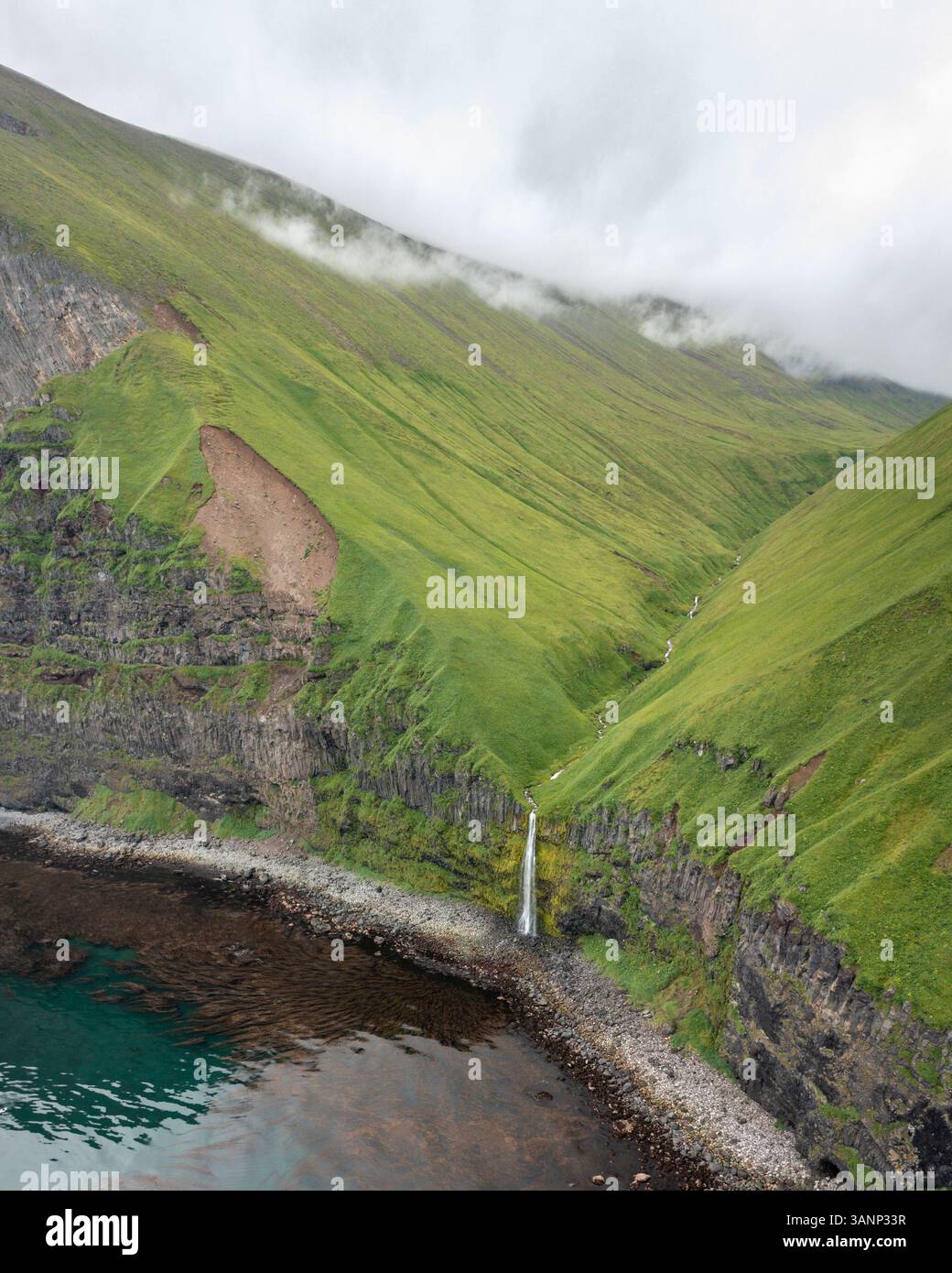 Aerial view of a waterfall along the coast, Driftwood Bay, Unalaska ...