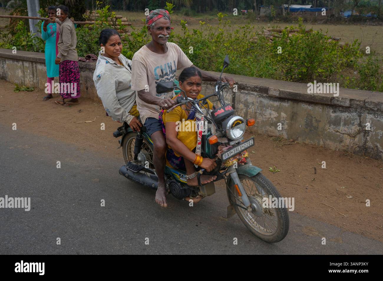 A man rides his motorcycle with two women as pillion riders in Andhra ...