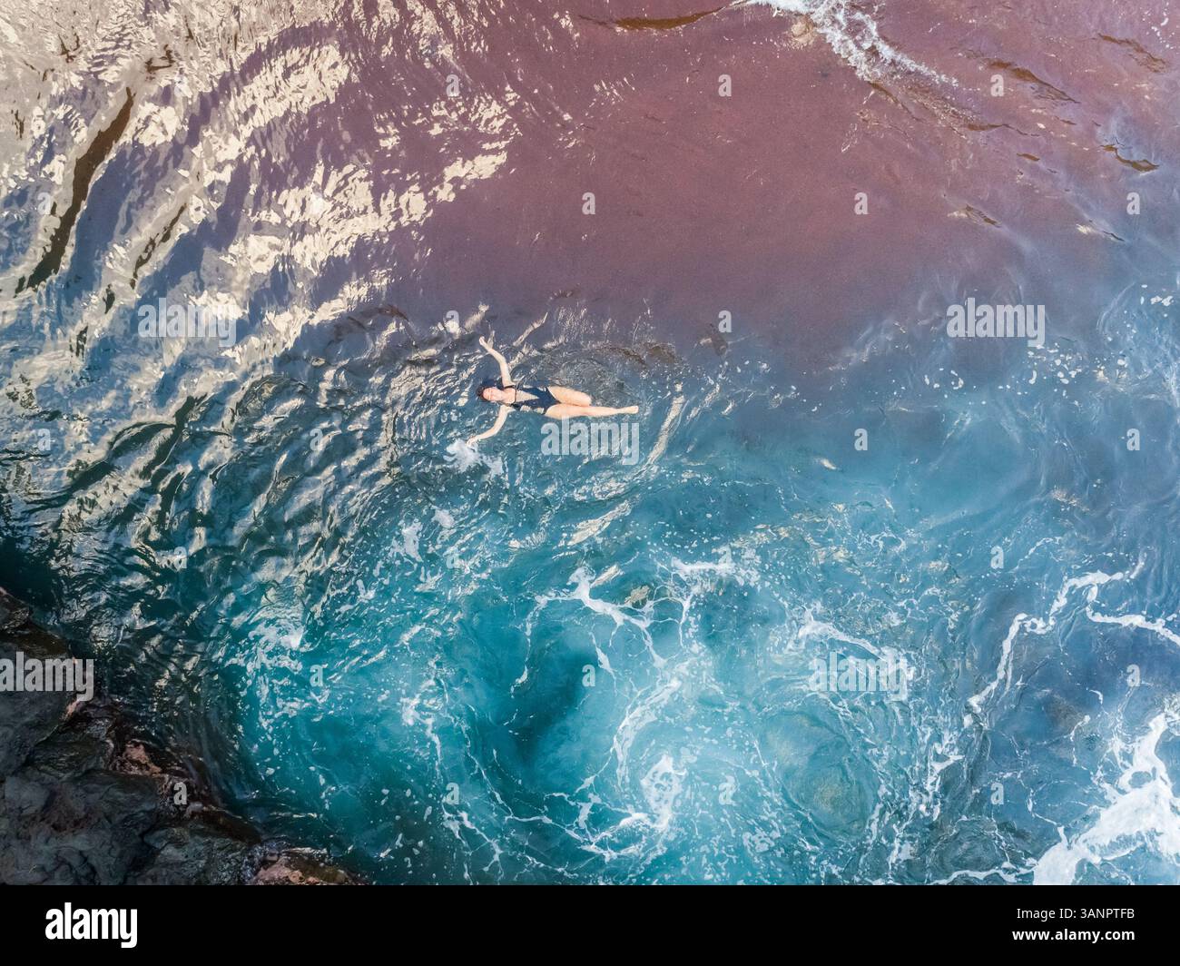Aerial view of an attractive woman swimming on transparent water ...