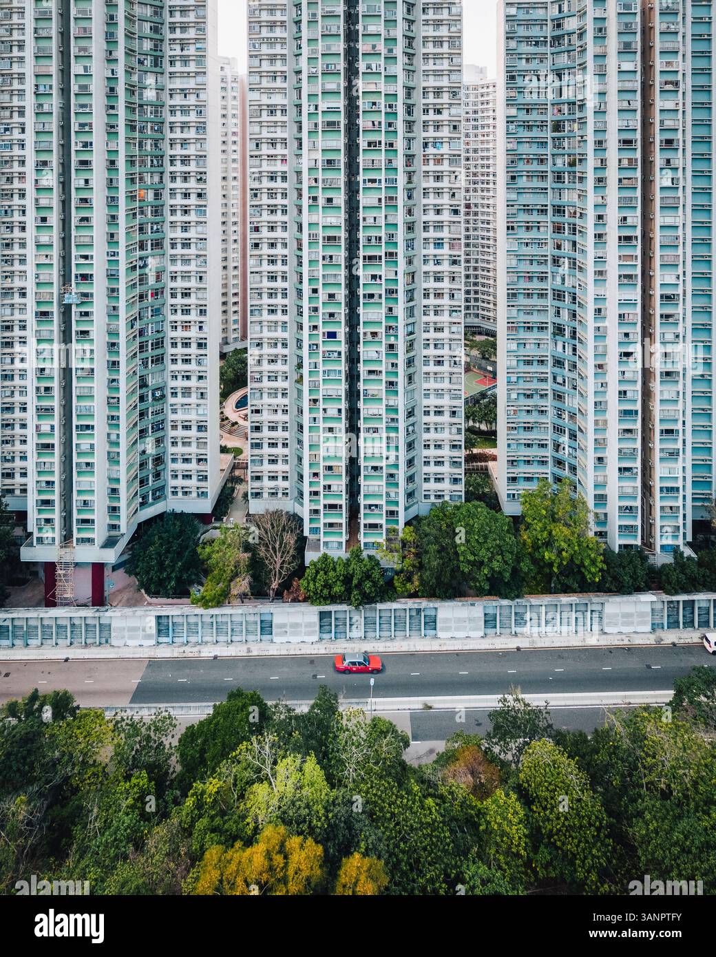 Aerial view of a car driving a road along a residential area with tall ...